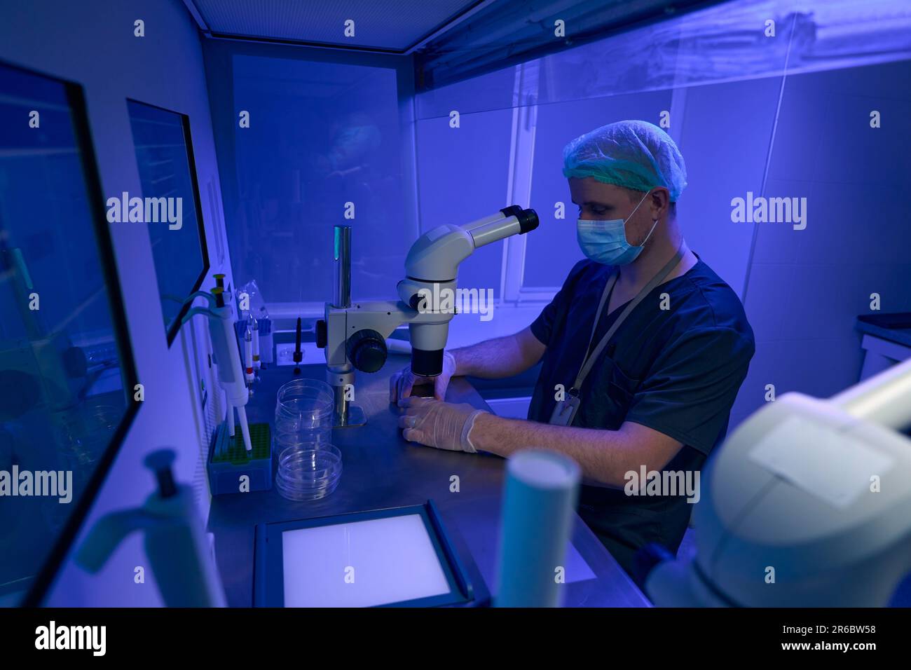 Man in sterile uniform conducting researches under microscope Stock ...