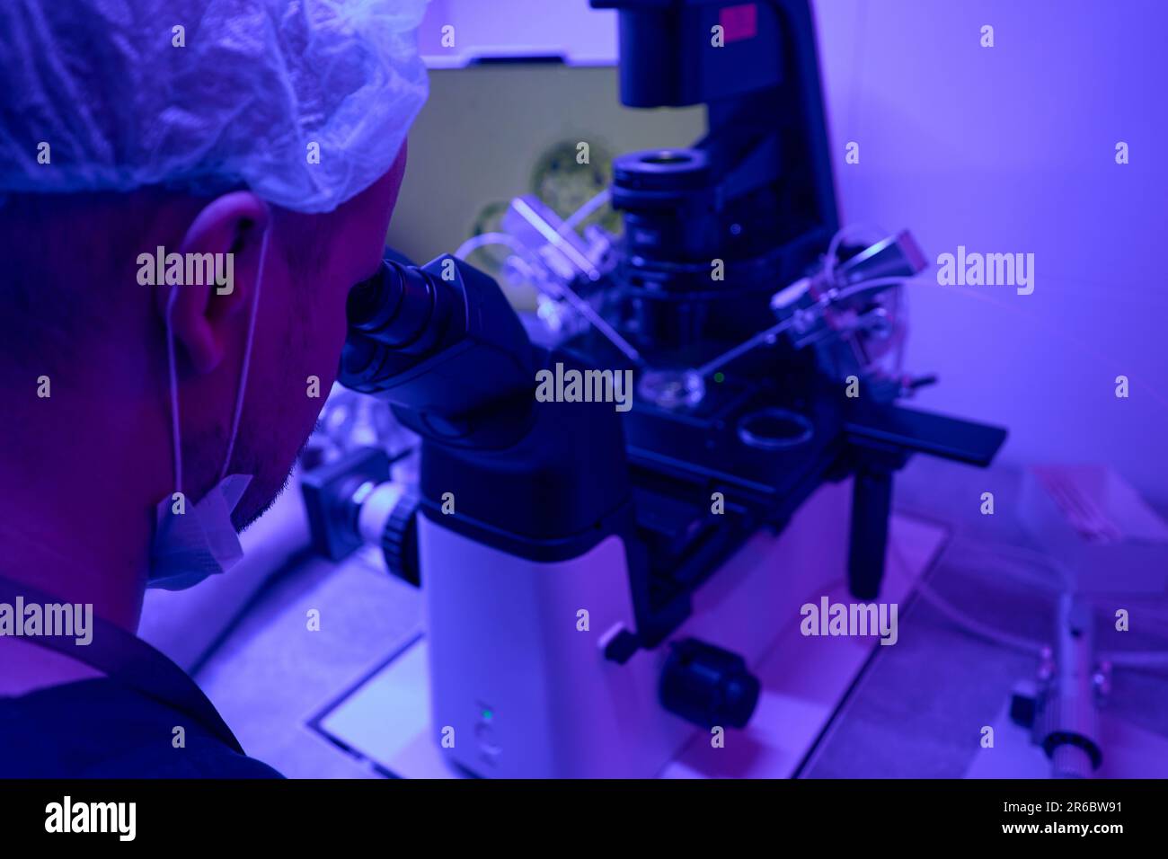 Concentrated man laboratory worker looking in microscope ocular lenses ...