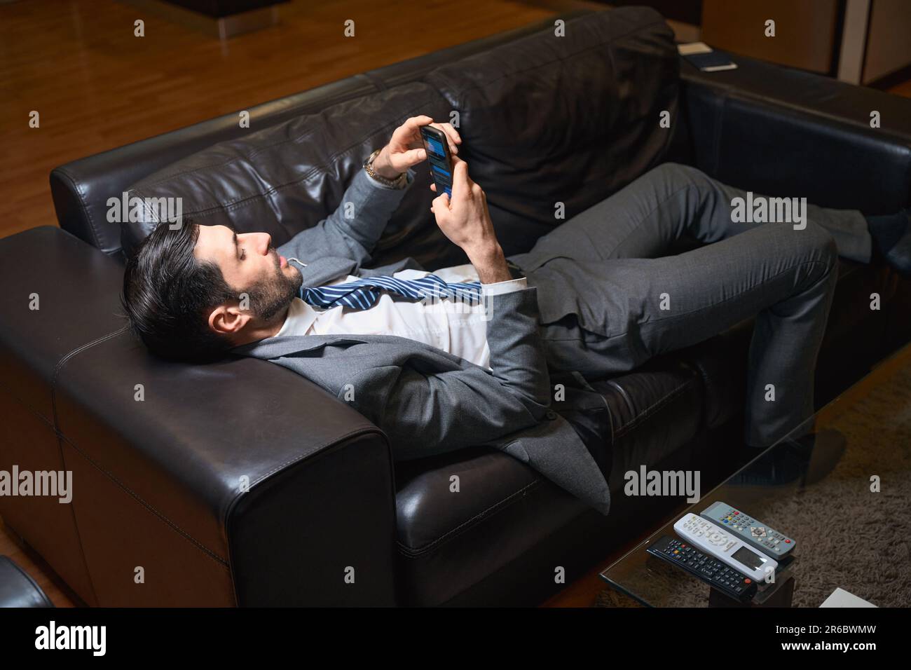 Man rests on a leather sofa in a hotel room Stock Photo - Alamy