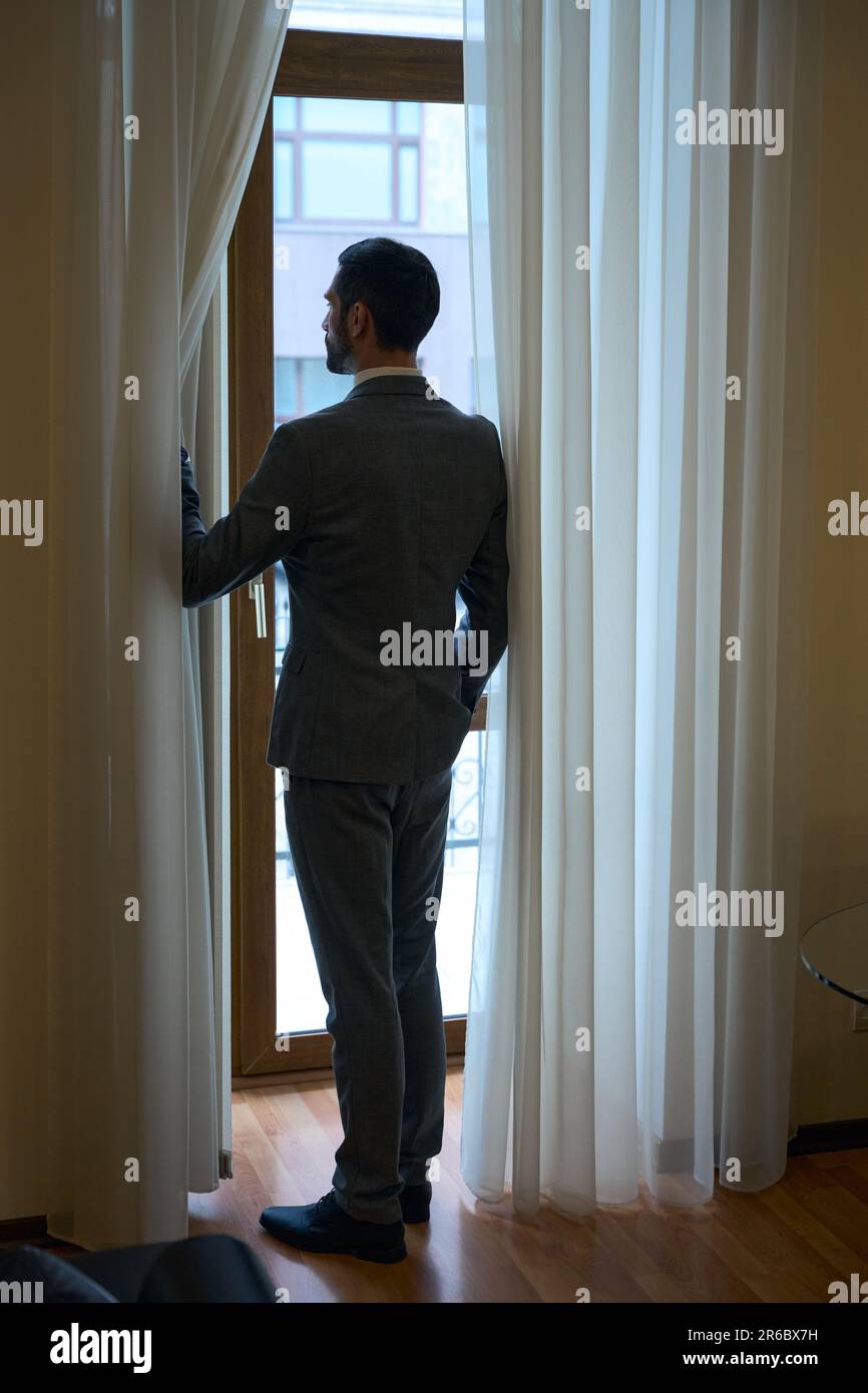 Elegant man in a business suit stands at french window Stock Photo - Alamy