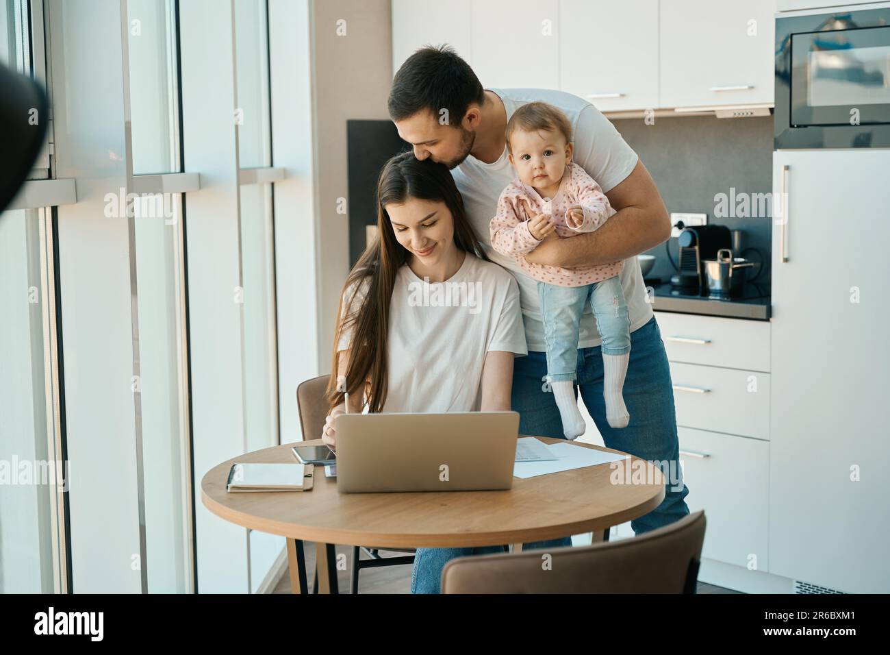 Husband kissing his wife working from home Stock Photo - Alamy