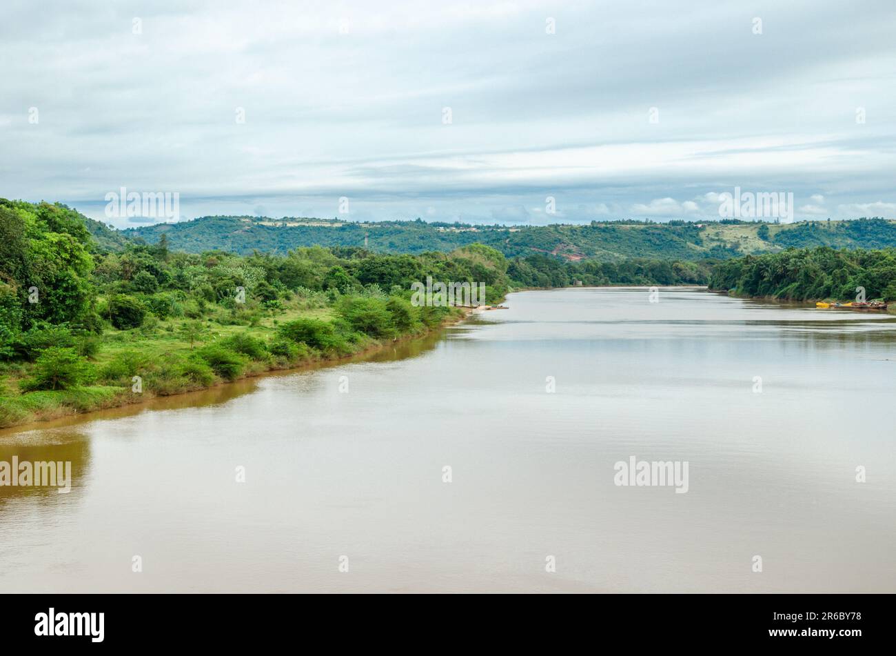 River with lush green river bank and muddy rain water at Polali ...
