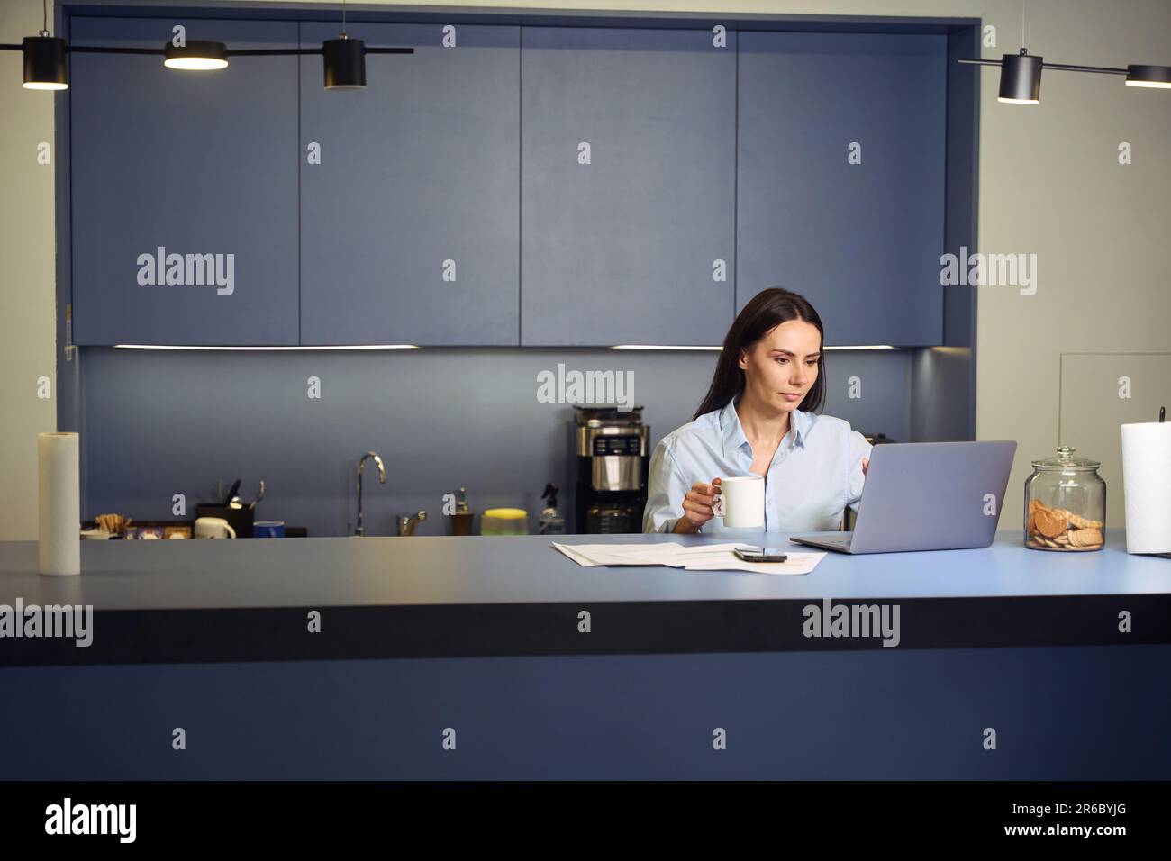 Serious company employee using her laptop during tea break Stock Photo ...