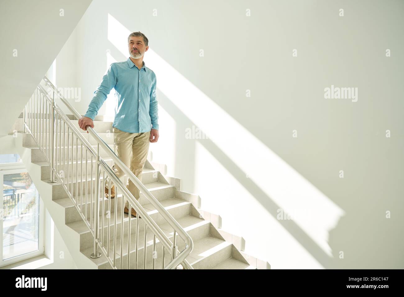 Handsome male holding handrails goes down steps of medical clinic Stock ...