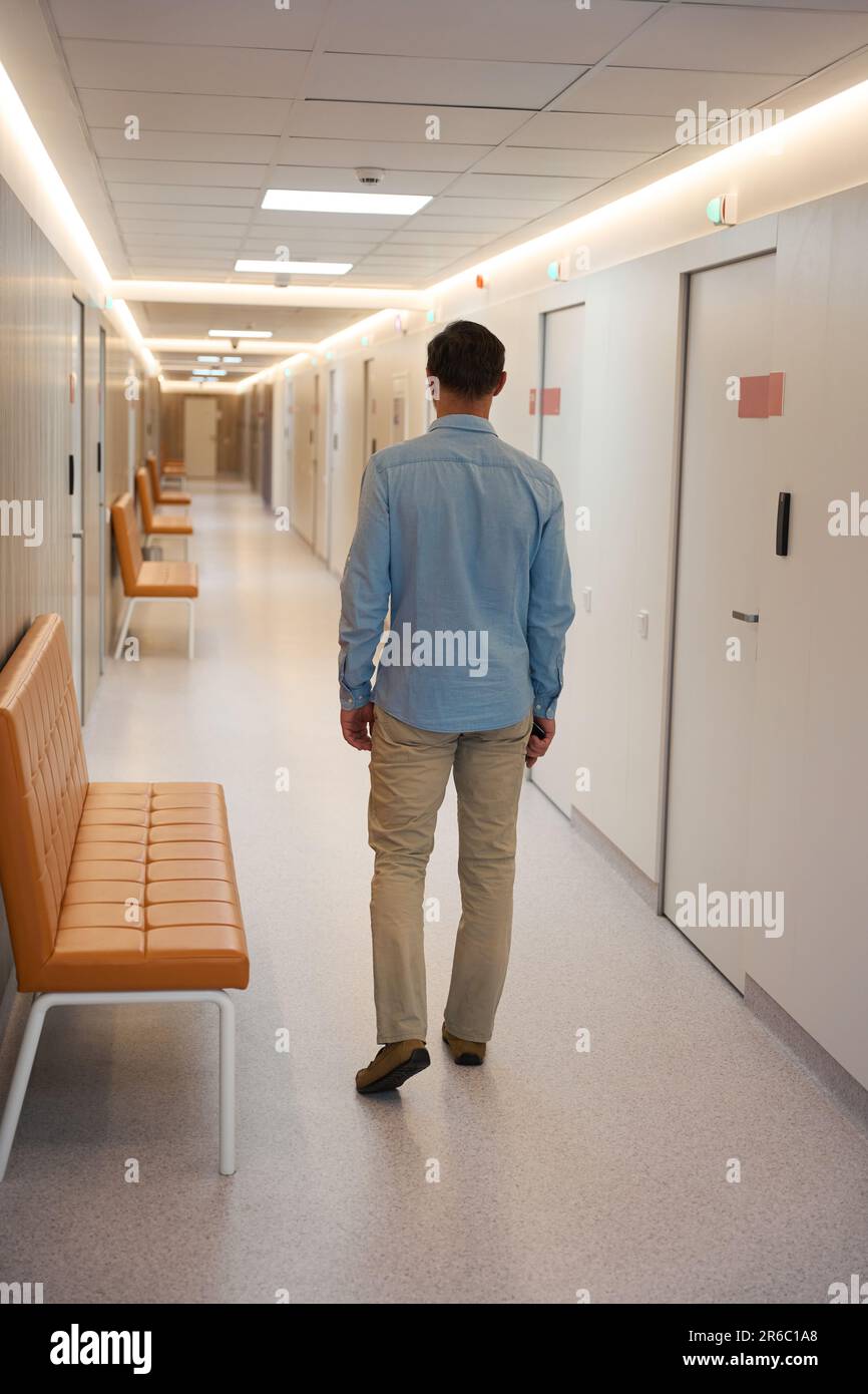 Man standing in hallway with sofas along wall. Back view Stock Photo ...
