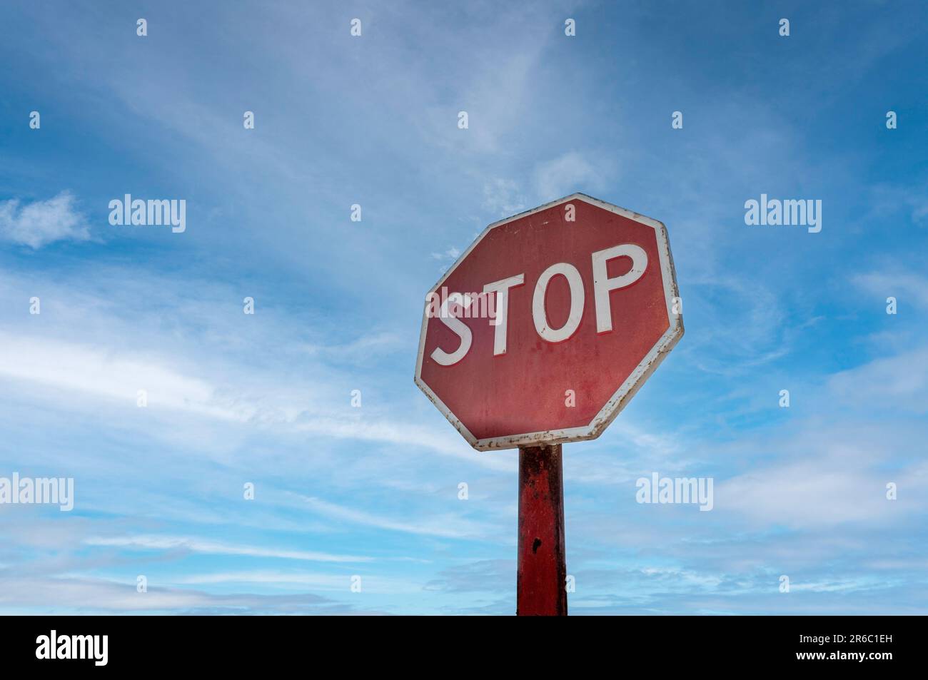 Red octagonal stop sign against a blue sky background Stock Photo - Alamy
