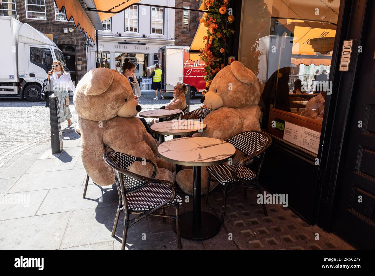 Two large toy bears sitting at tables outside a cafe, West End of ...