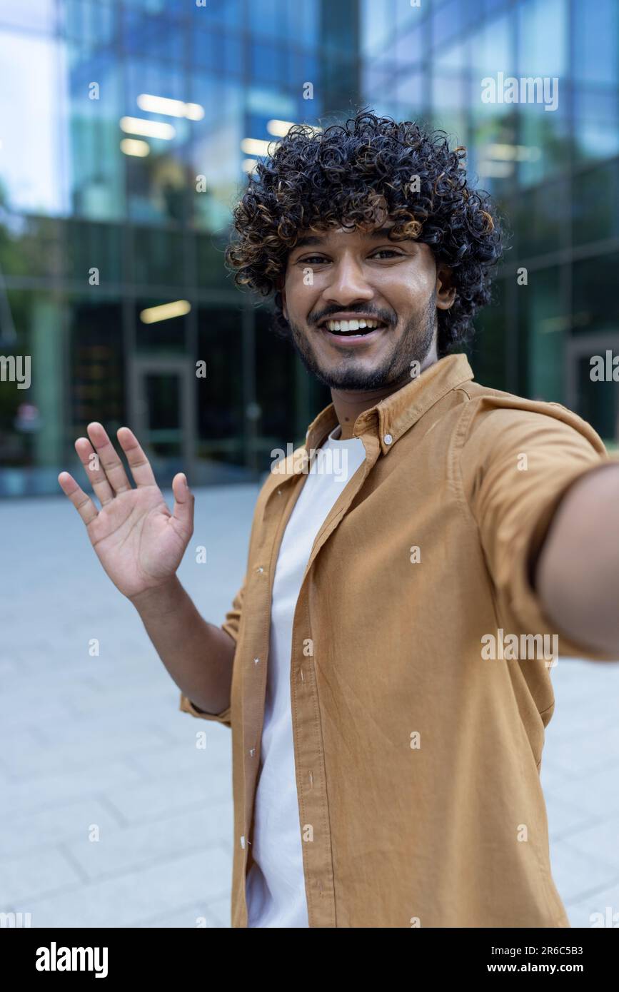 Vertical photo. Young smiling male hispanic student talking on video ...
