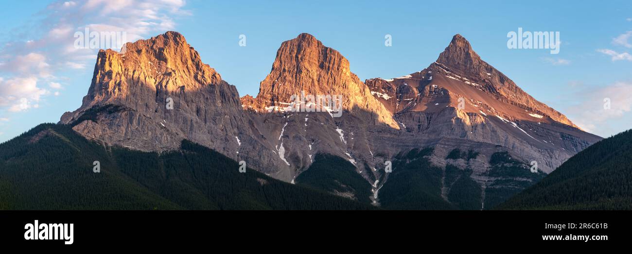 Golden sunset peaks near Banff National Park with Three Sisters at Canmore in view. Sun shining ...