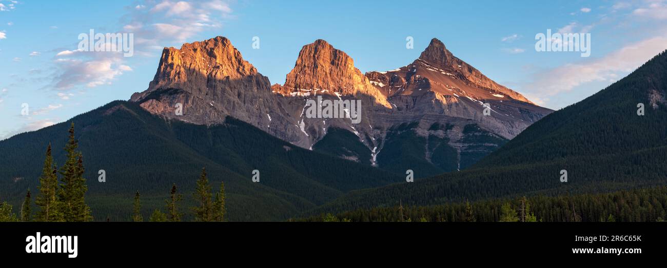Golden sunset peaks near Banff National Park with Three Sisters at Canmore in view. Sun shining ...