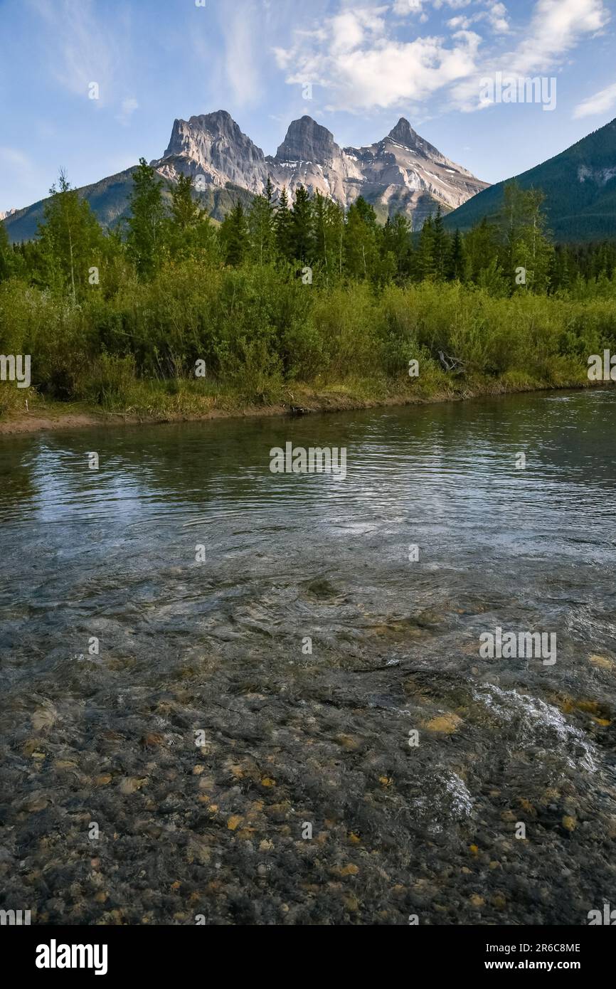 Mountain peaks reflecting in the calm water below at Three Sisters in Canmore, near Banff ...