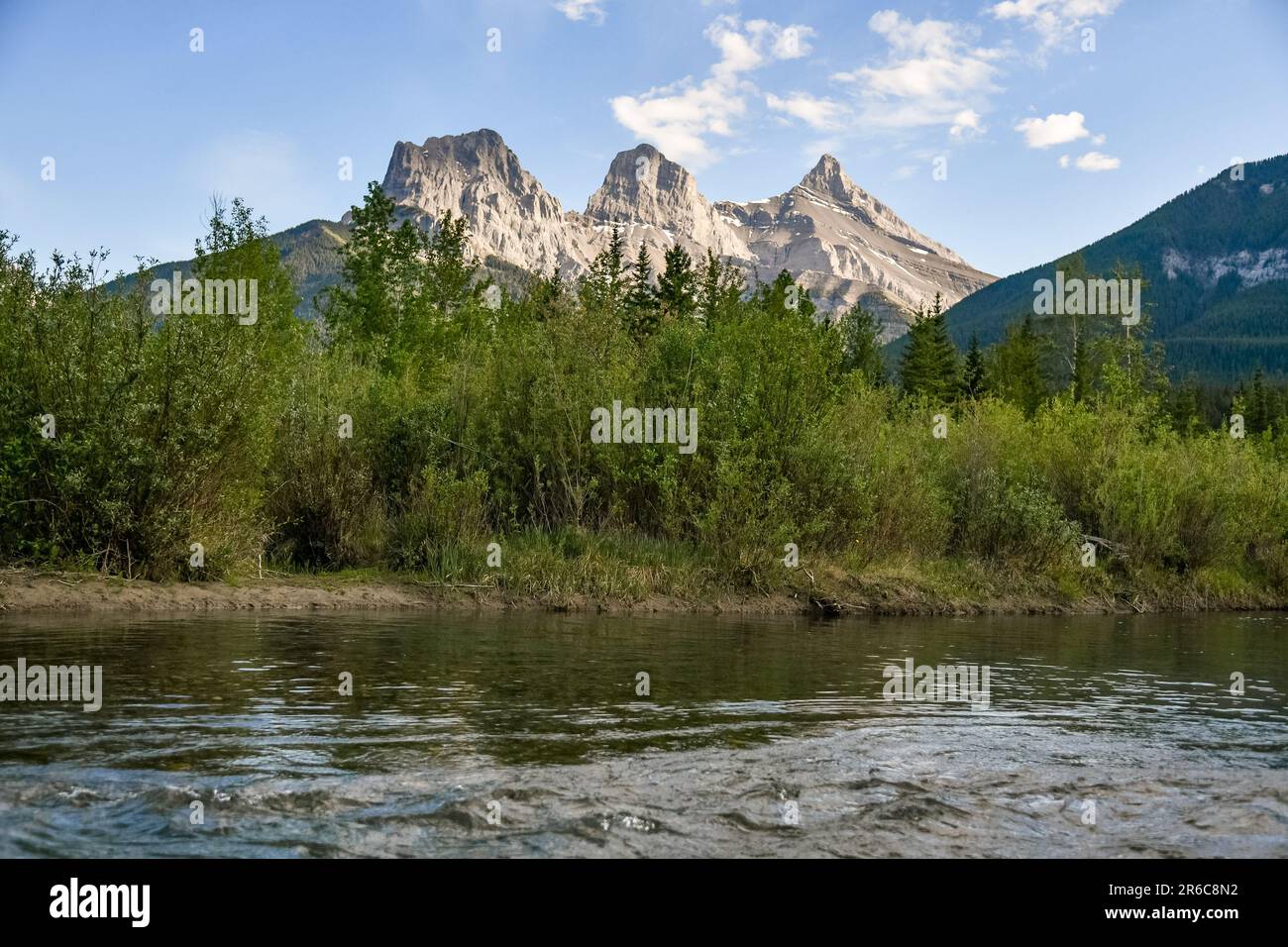 Mountain peaks reflecting in the calm water below at Three Sisters in Canmore, near Banff ...