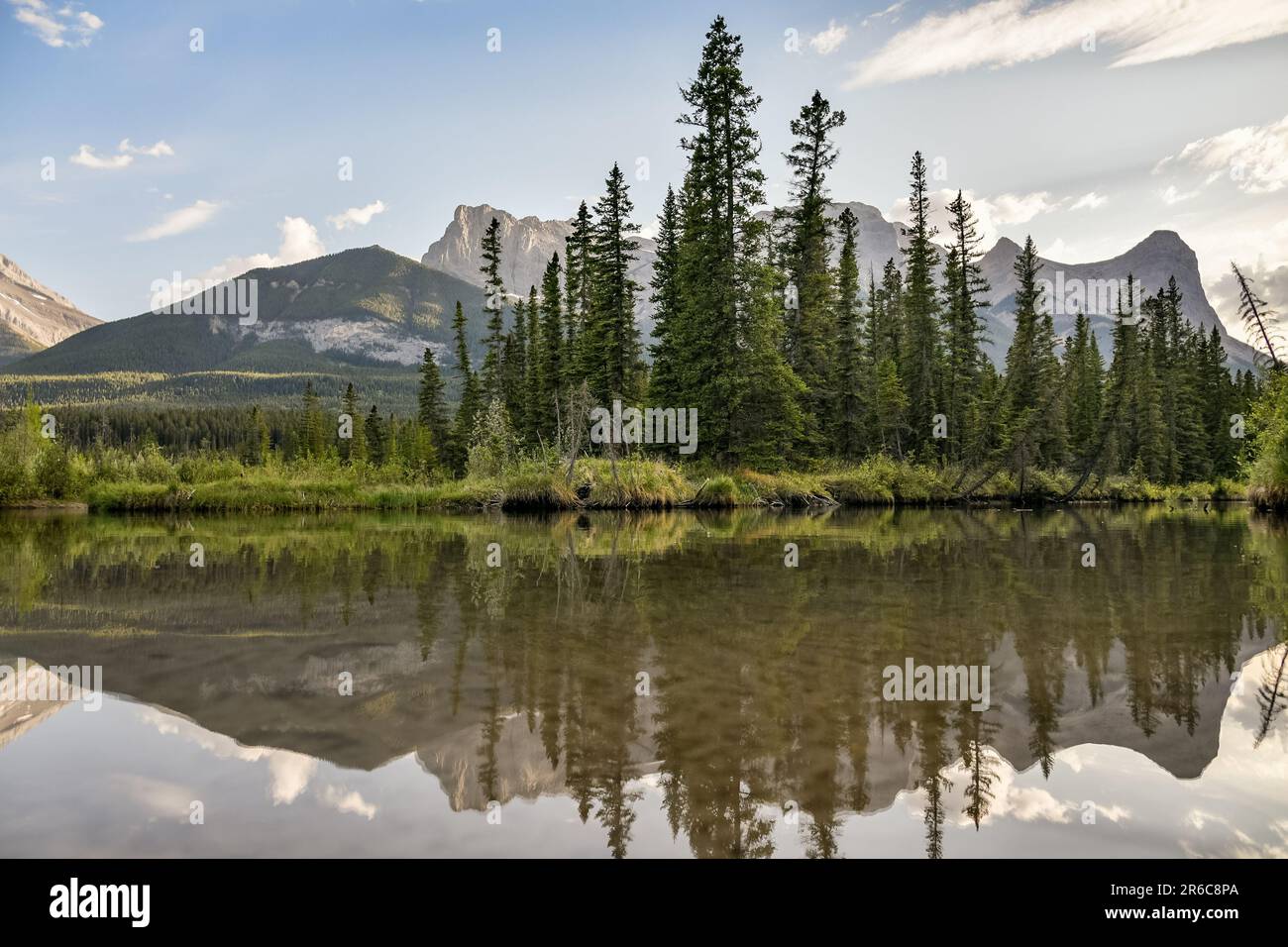 Mountain peaks reflecting in the calm water below at Three Sisters in ...