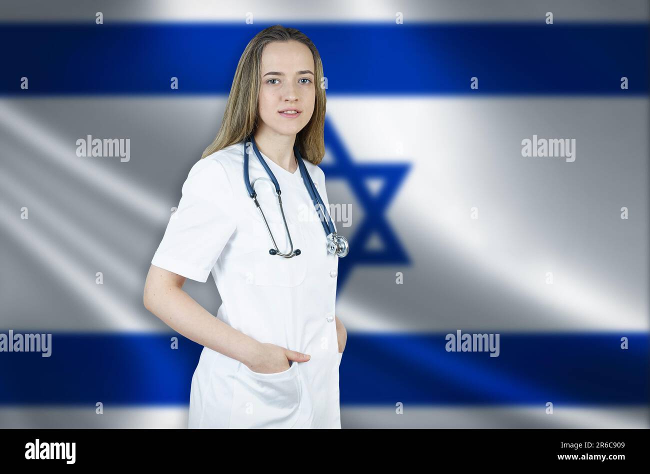 A young female doctor in a white coat and a stethoscope stands on the ...