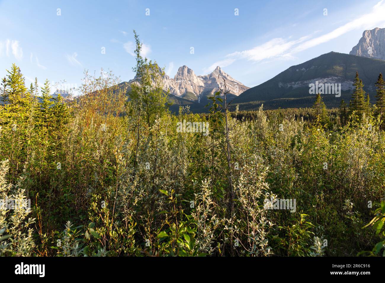 Mountain peaks reflecting in the calm water below at Three Sisters in Canmore, near Banff ...