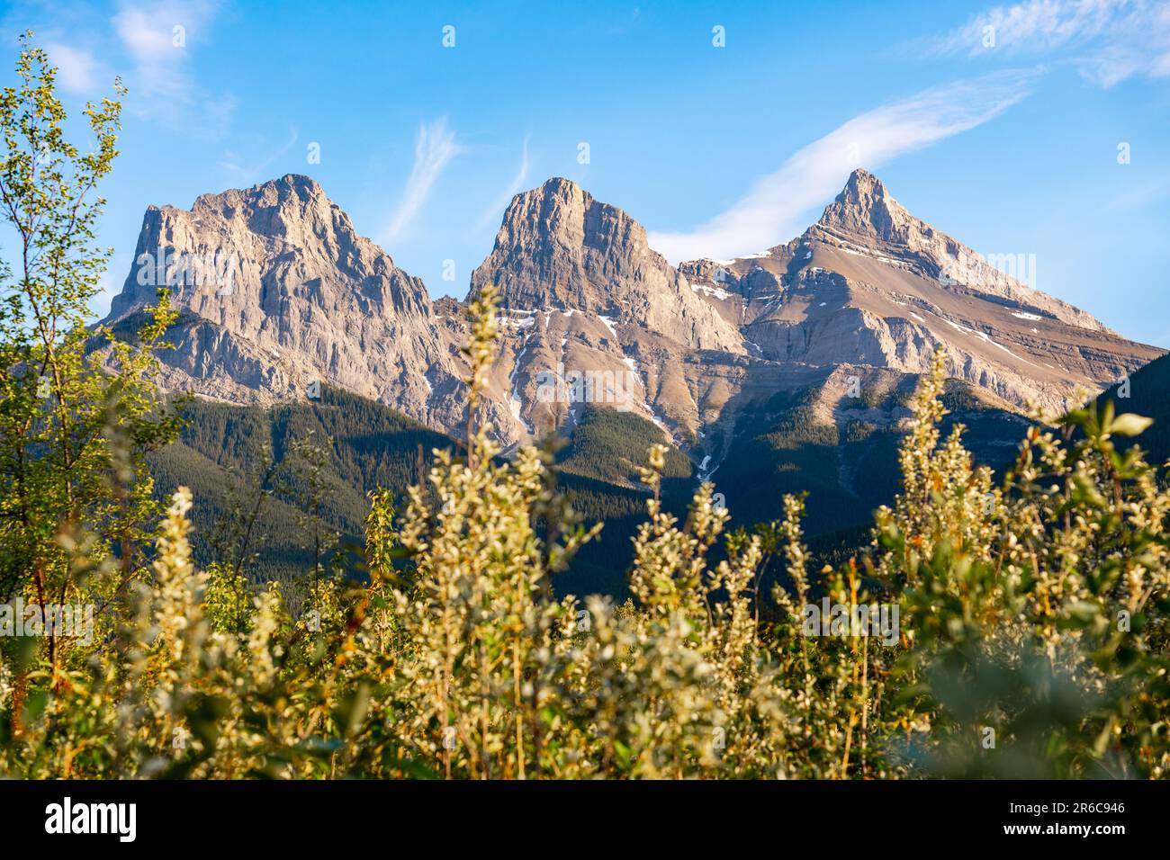 Mountain peaks reflecting in the calm water below at Three Sisters in Canmore, near Banff ...