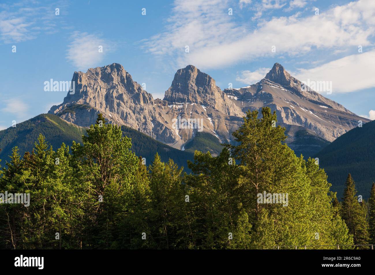 Mountain peaks reflecting in the calm water below at Three Sisters in Canmore, near Banff ...