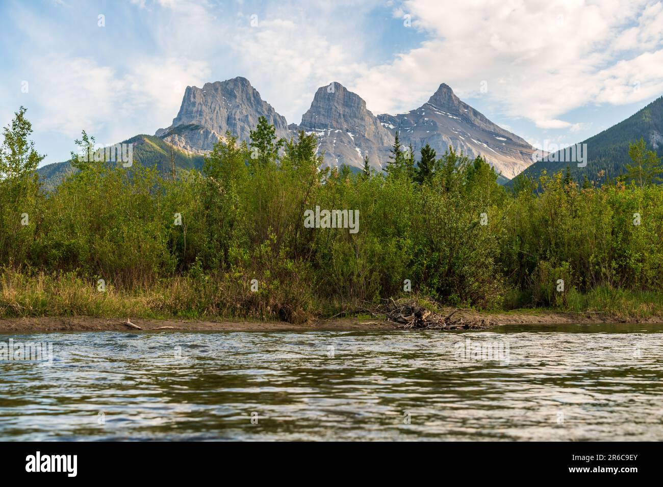 Mountain peaks reflecting in the calm water below at Three Sisters in Canmore, near Banff ...