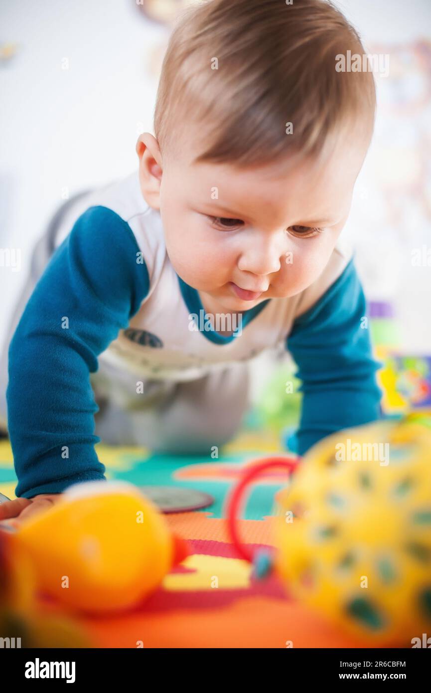 Cute baby boy crawls and explore things around, surrounded with ...