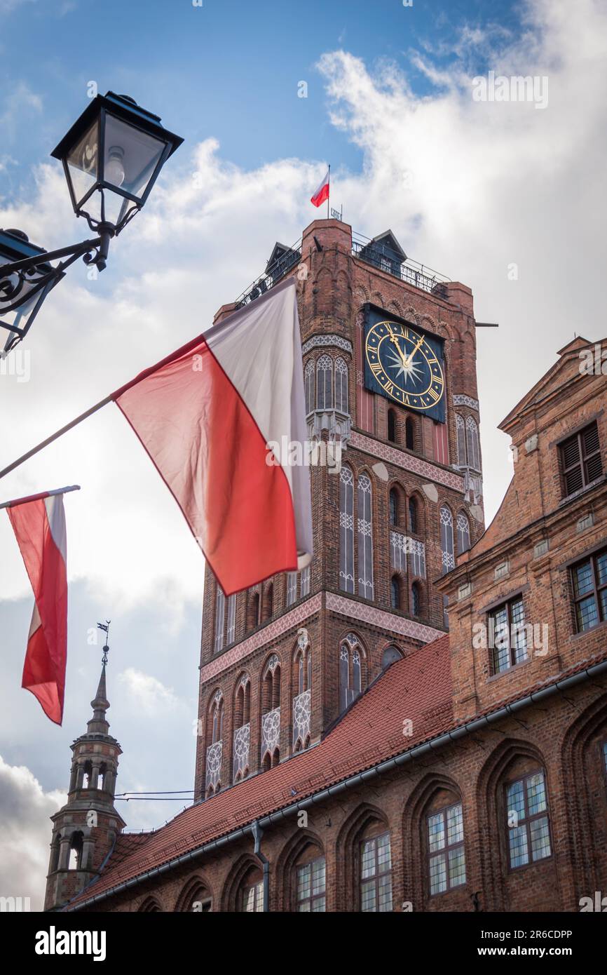 Two Polish flags hanging with Torun city hall ratusz tower in the ...