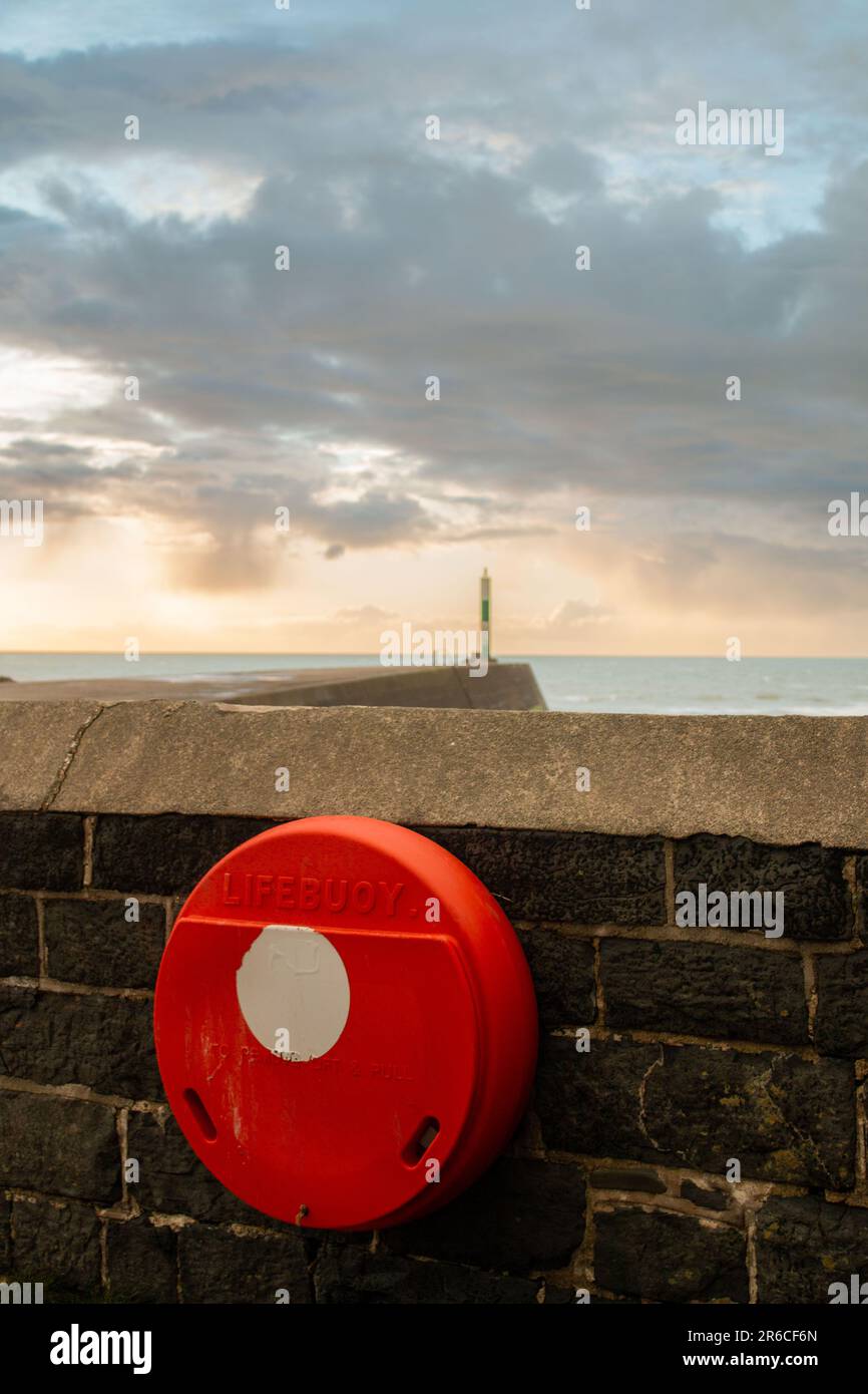 Lifebuoy on a wall with a lighthouse in background, Tan Y Bwlch ...