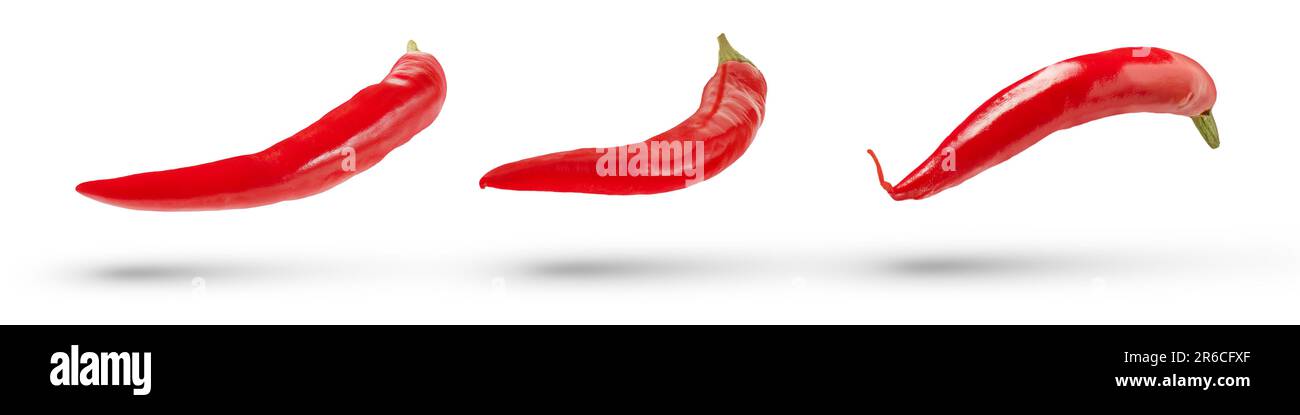 Pods of red hot peppers of various sizes and shapes fall on a white ...