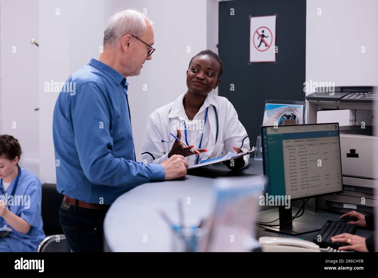 Young adult doctor putting elderly patient to sign medical documents ...