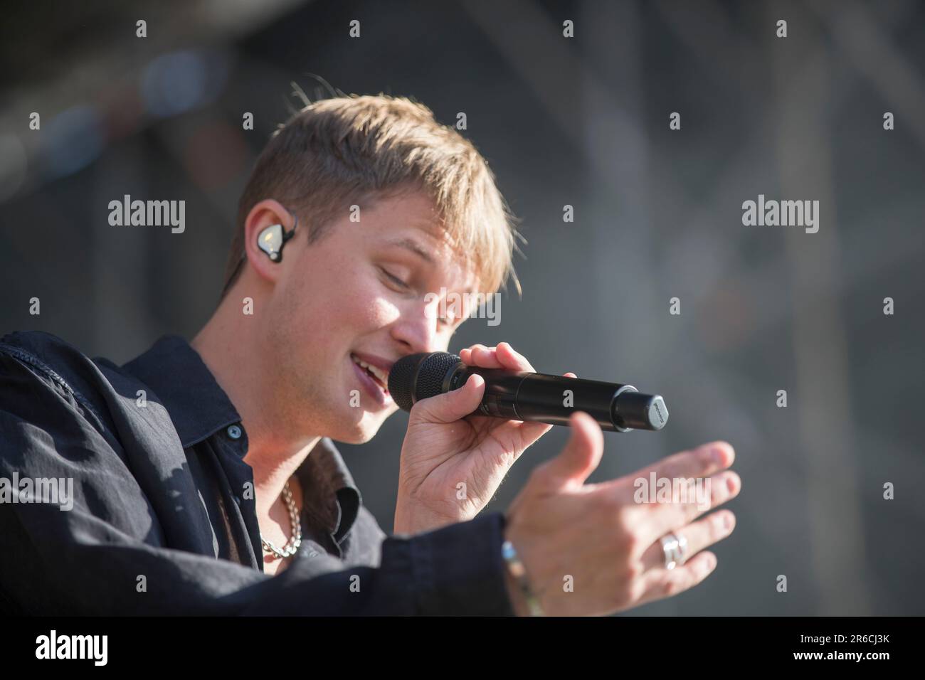 A young man wearing earbuds and headphones singing into a microphone ...