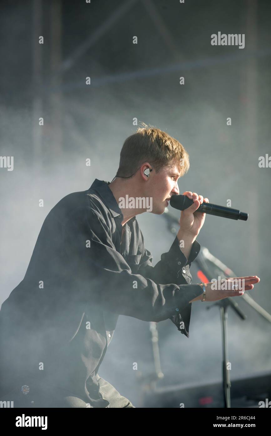 A man stands on a stage singing passionately into a microphone while ...