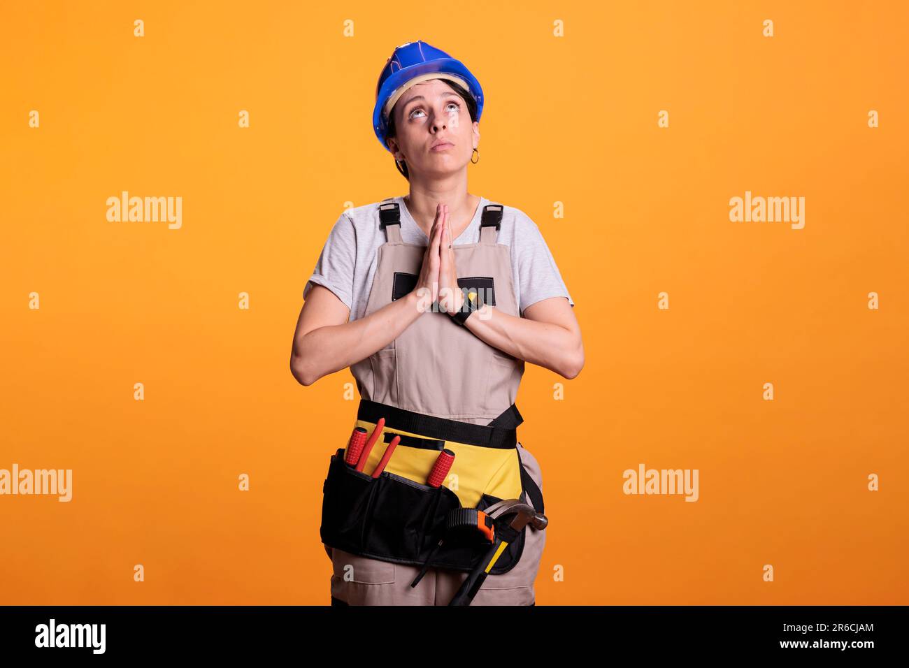 Female building engineer doing prayer hands symbol on camera, begging ...