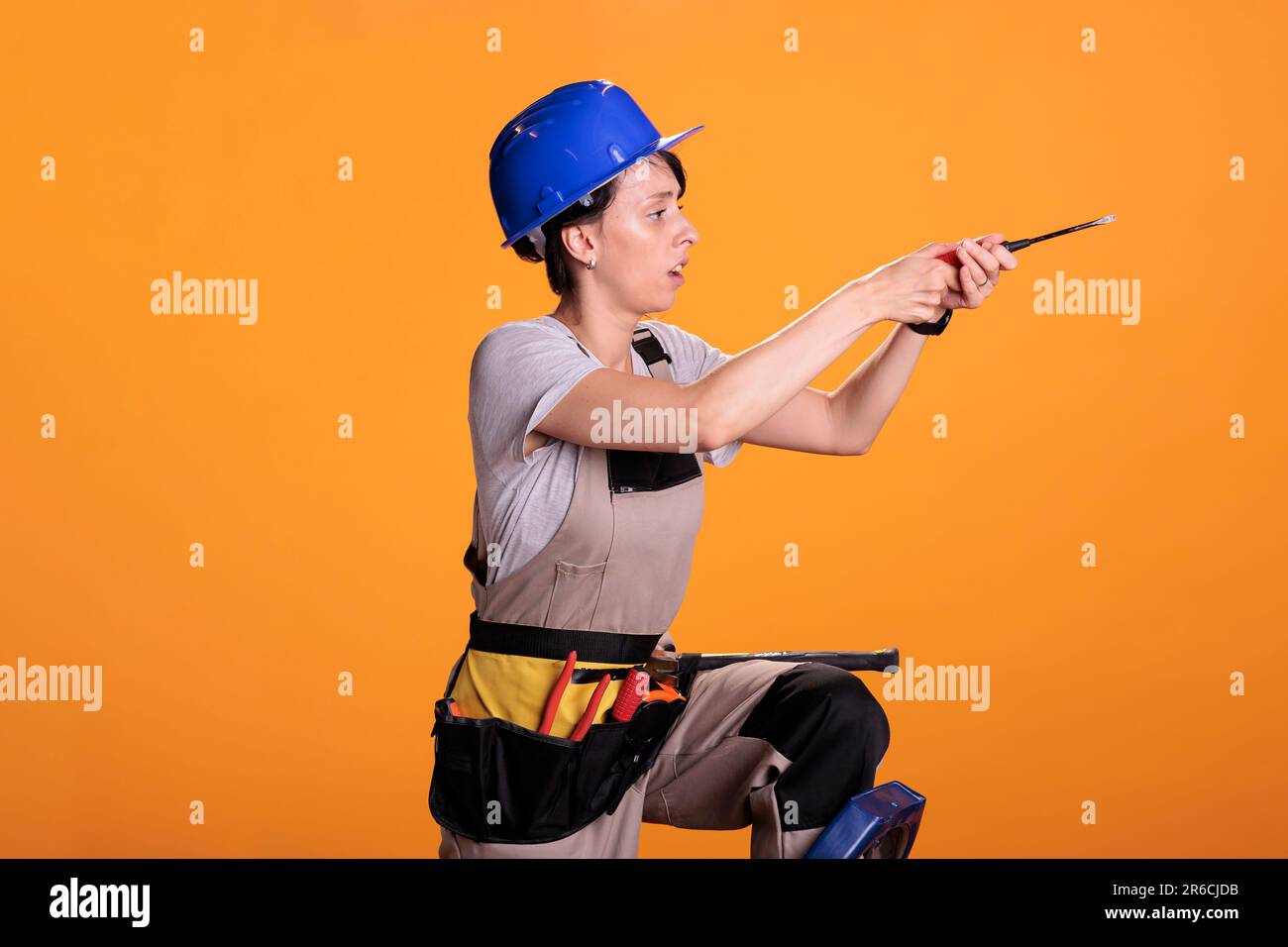 Construction worker on ladder repairing wall with screwdriver, posing ...