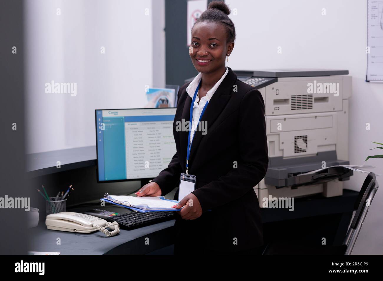 Portrait of receptionist in black suit standing at hospital counter ...