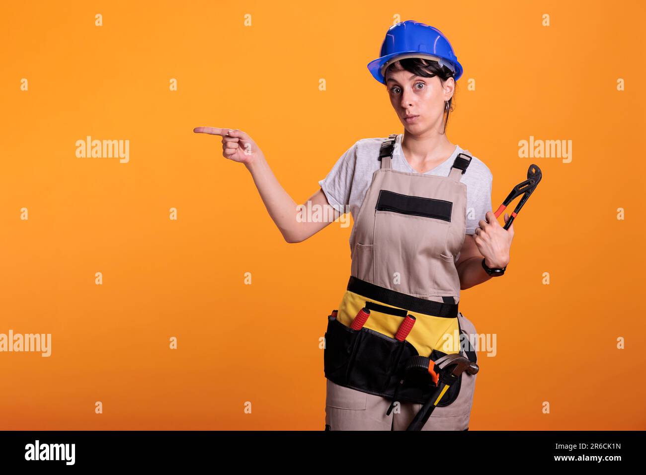 Woman builder indicating direction on left side of studio, posing with ...