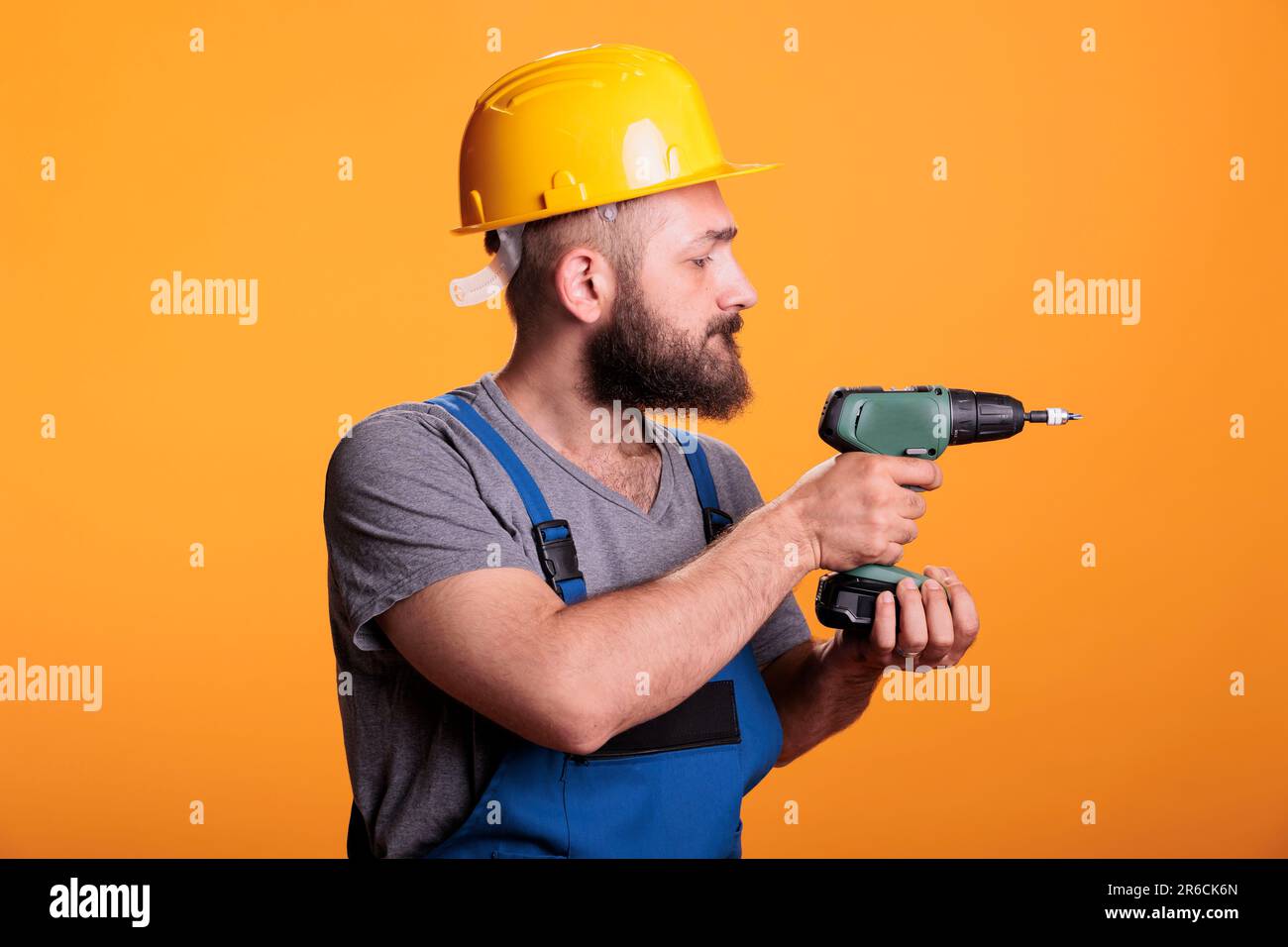 Professional craftsman working wtih electric power drill tool, wearing ...