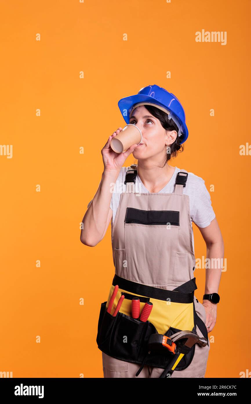 Construction worker serving coffee cup after renovation, using building tools to restore and ...