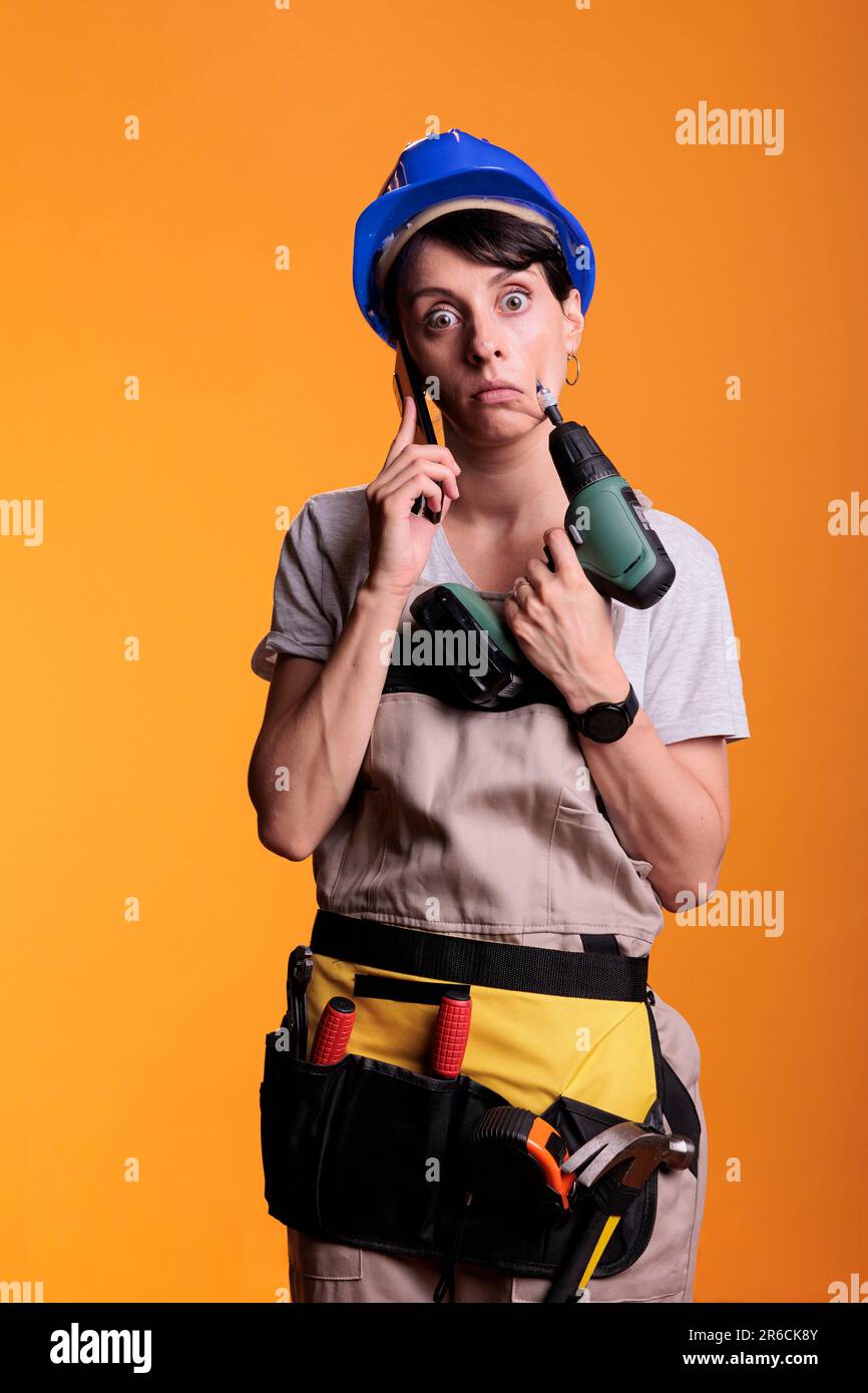 Bored construction worker answering smartphone call, posing over yellow ...