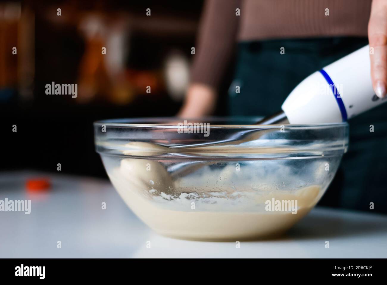 A skilled chef's hand prepares homemade mayonnaise by beating together ...