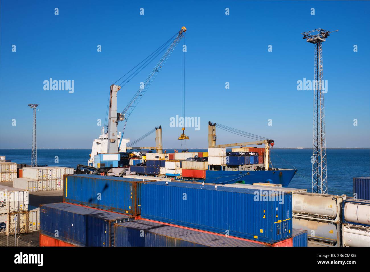 Port crane loading container ship with containers and cars in port ...