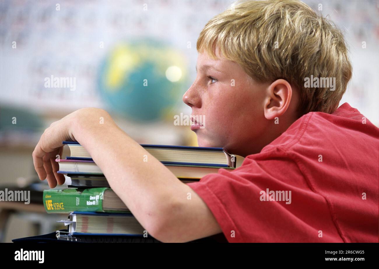 worn out boy in school not paying attention in class, leaning on a ...