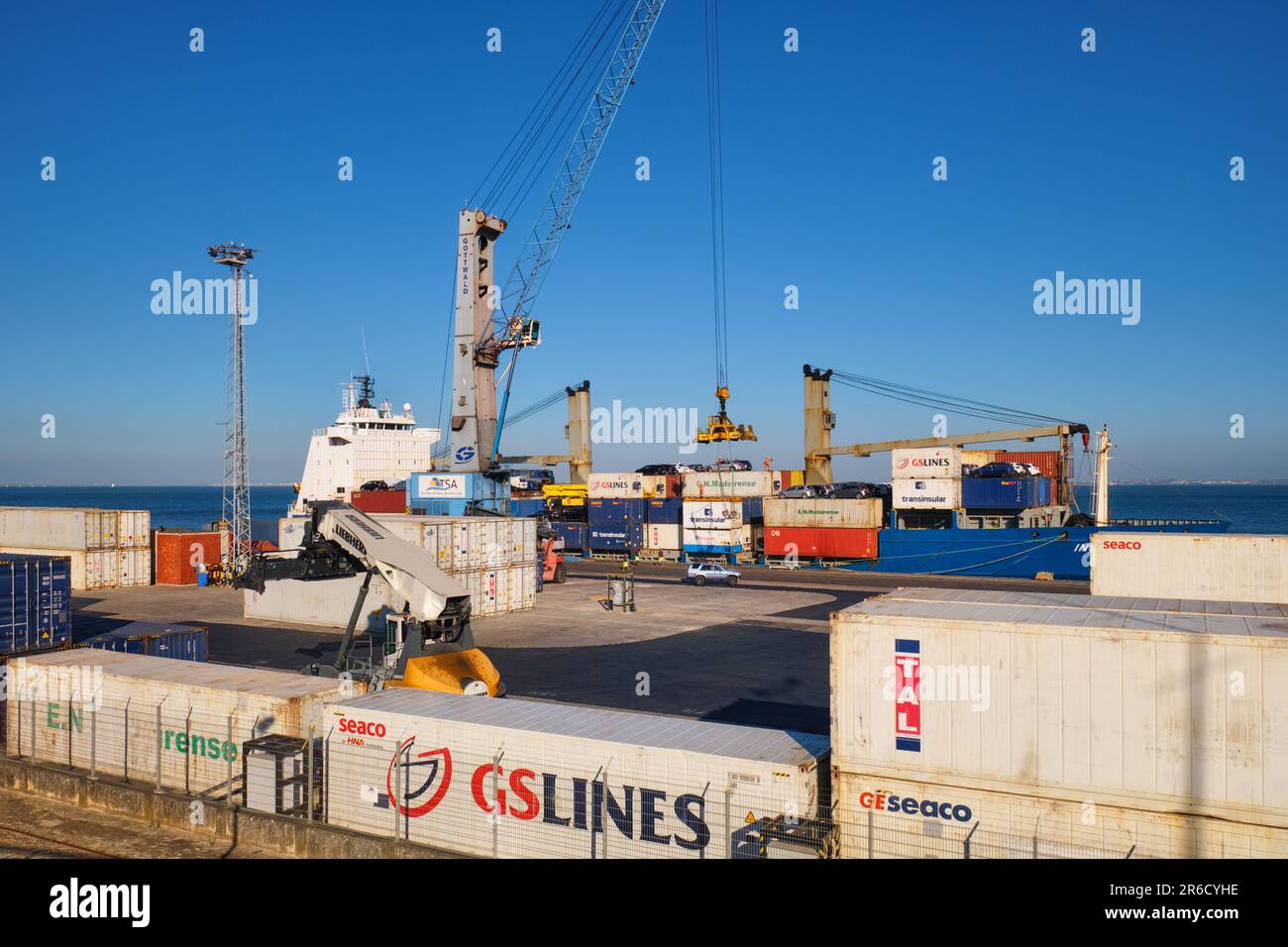 Port crane loading container ship with containers and cars in port ...