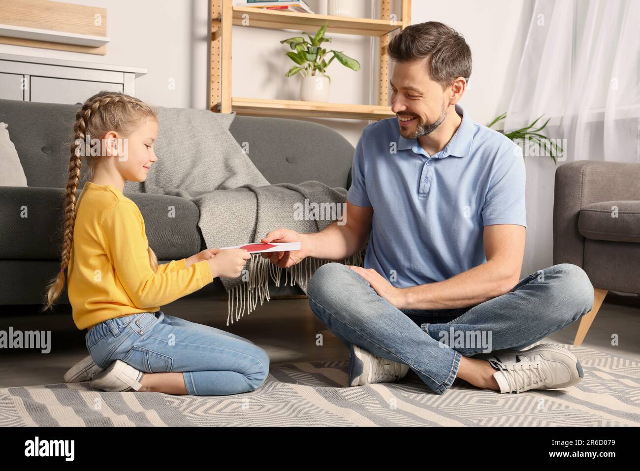 Happy man receiving greeting card from his little daughter at home ...