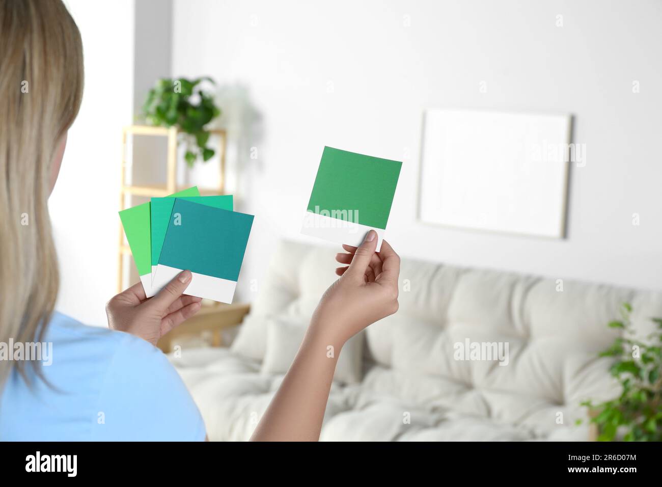 Woman choosing paint shade for wall in room, focus on hands with color ...