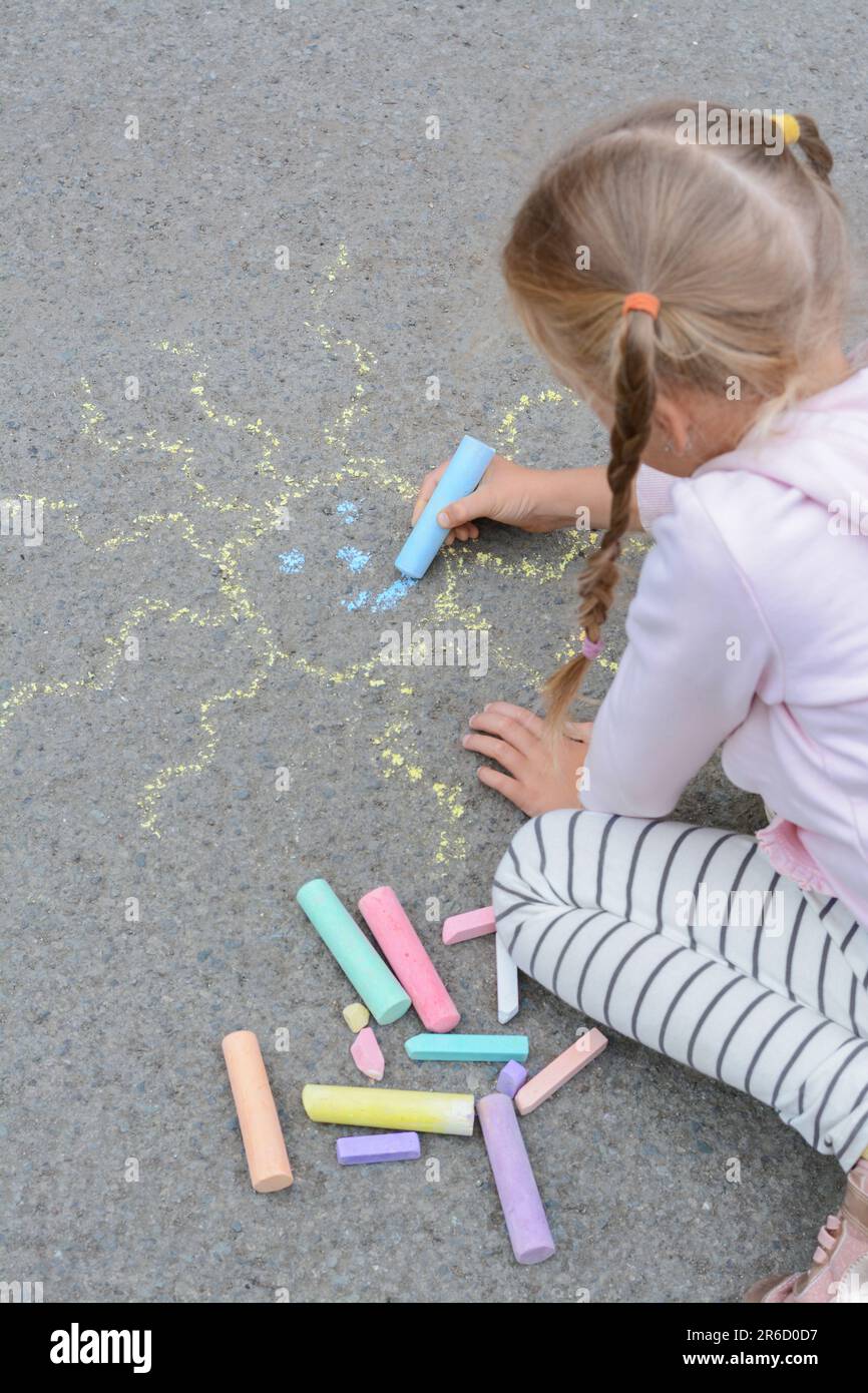 Little child drawing sun with chalk on asphalt Stock Photo - Alamy