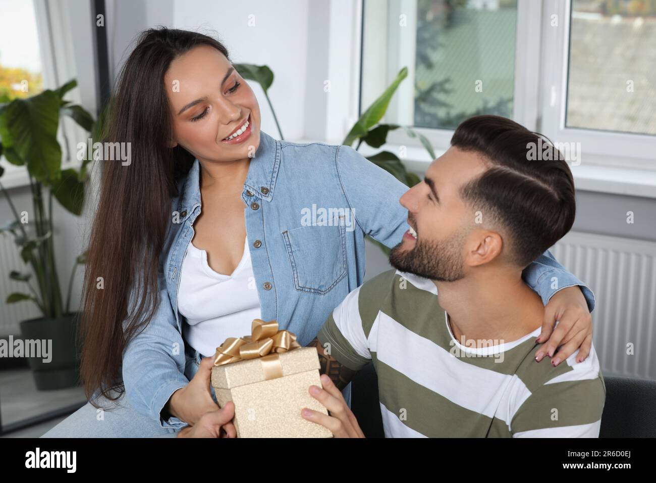 Woman presenting gift to her boyfriend at home Stock Photo - Alamy