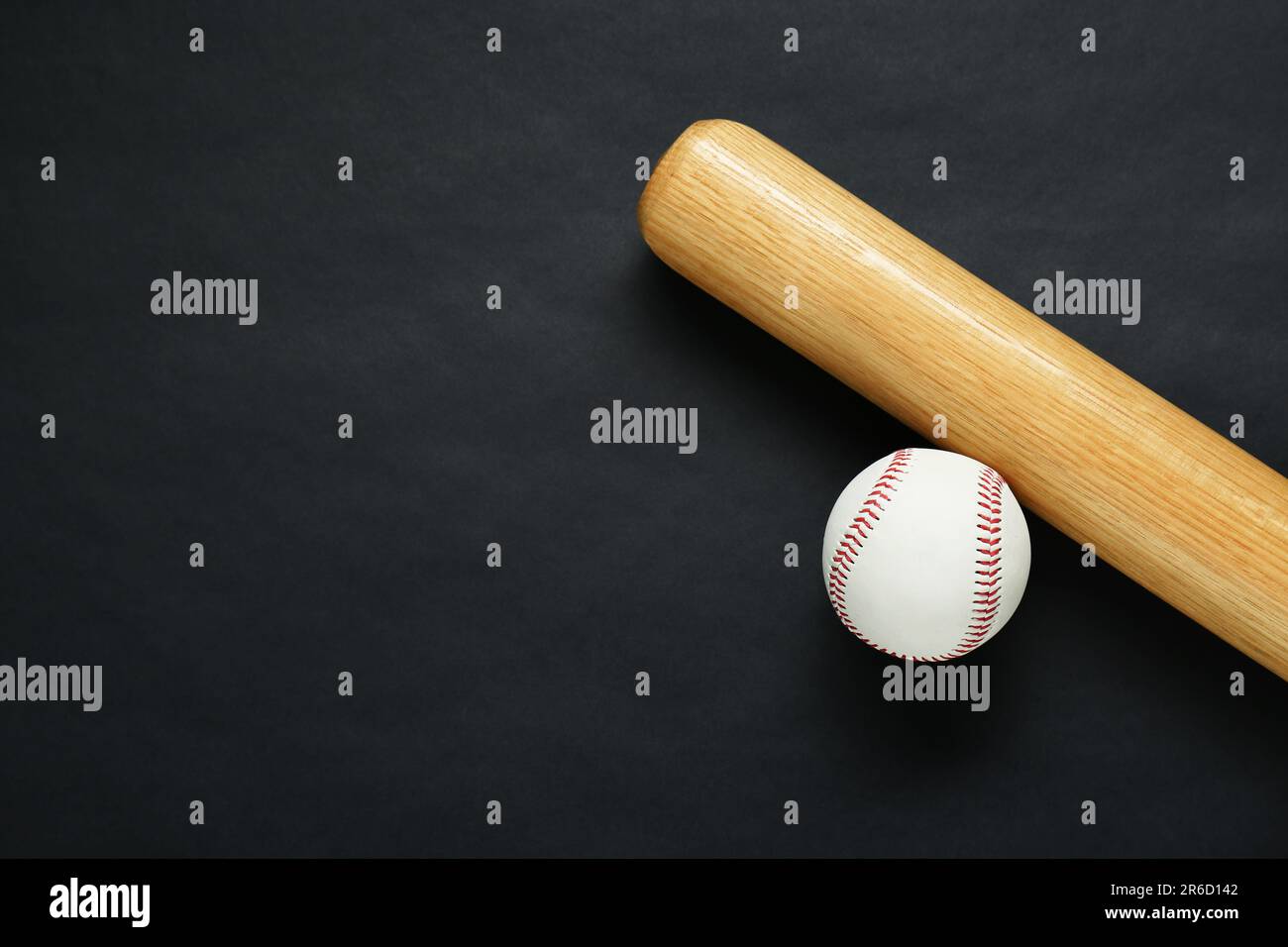 Wooden baseball bat and ball on black background, flat lay. Space for ...