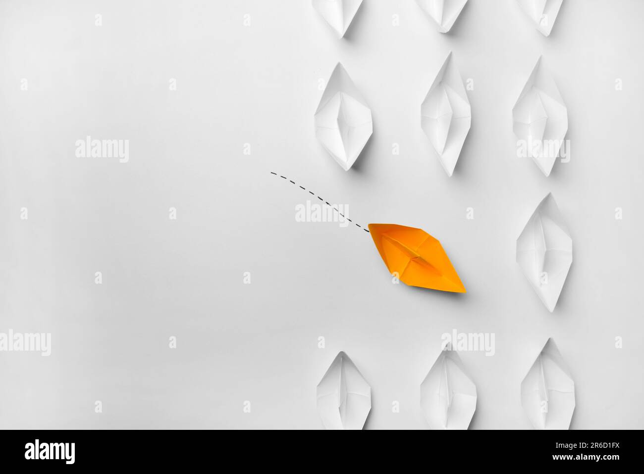 Yellow paper boat floating to others on white background, flat lay with ...