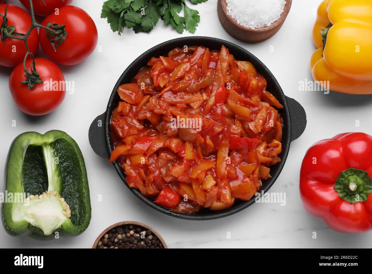 Delicious lecho in frying pan and ingredients on white table, flat lay ...