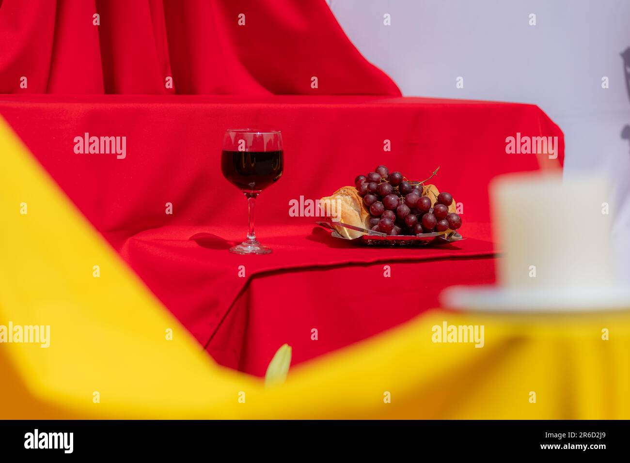 Wine glass, bread and grapes on red cloth in hard light. Symbolism of ...
