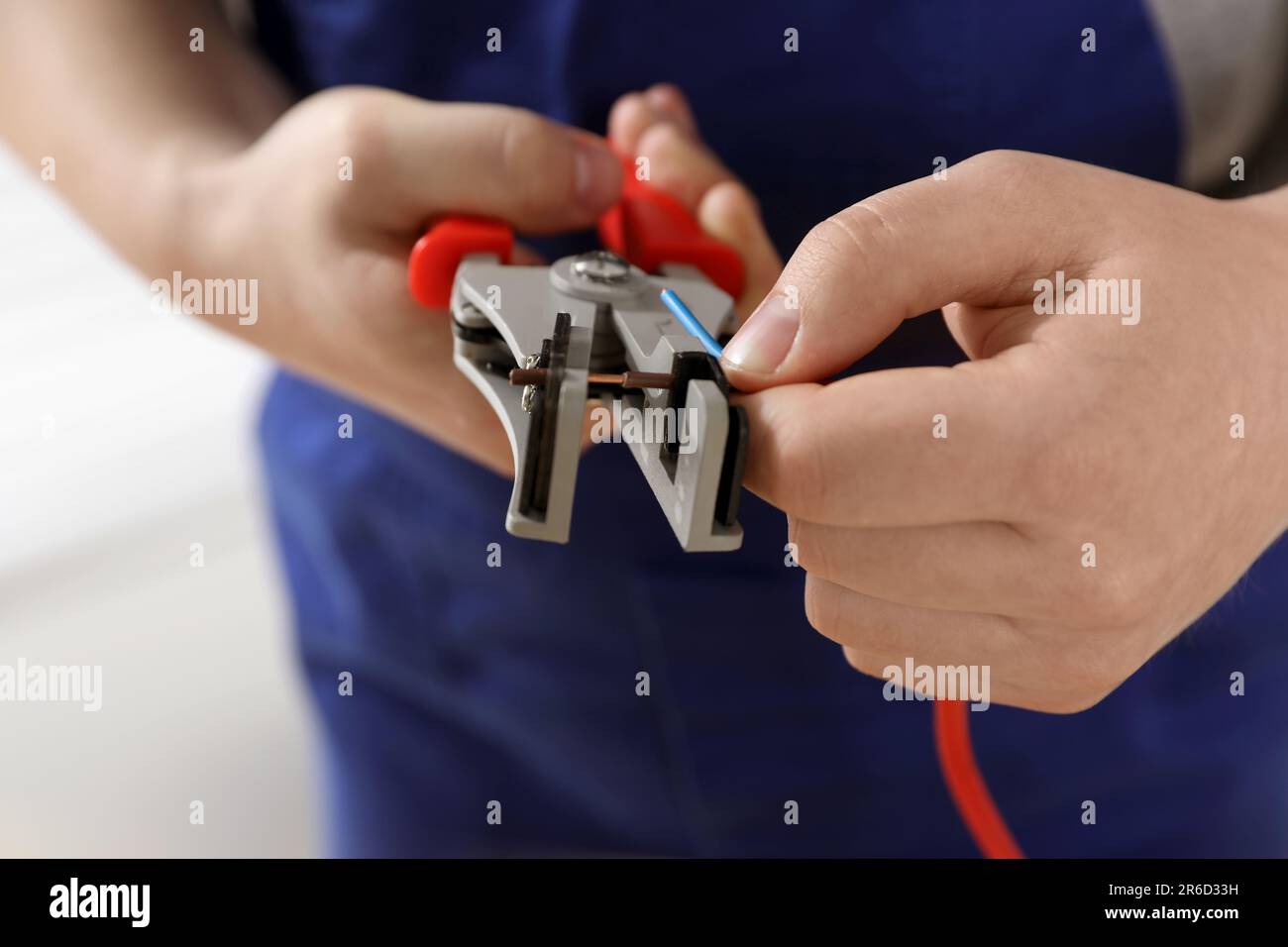 Professional electrician in uniform stripping wiring, closeup view ...