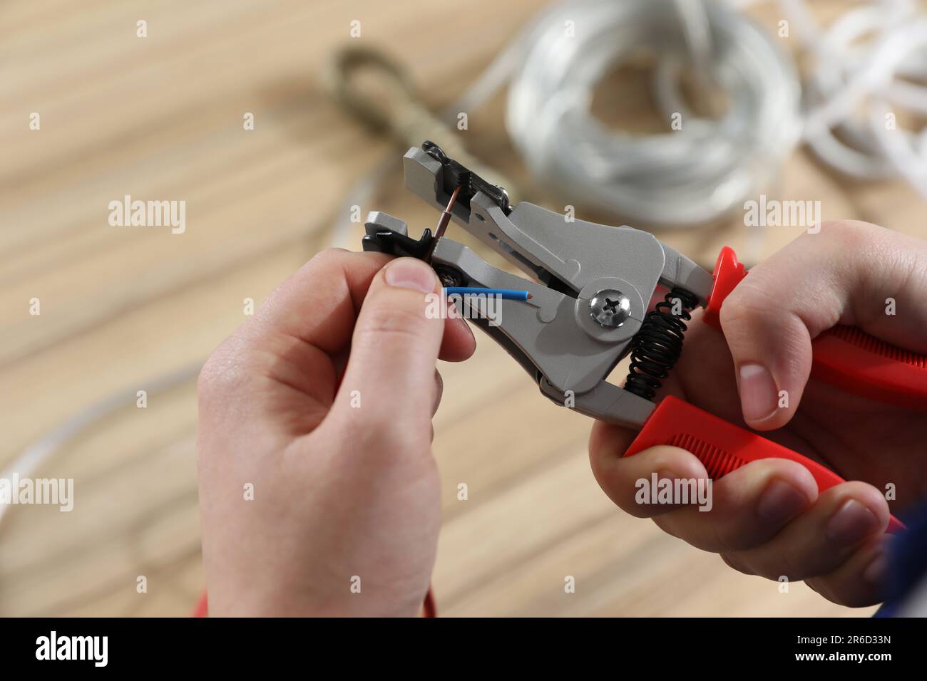 Professional electrician stripping wiring at wooden table, above view ...